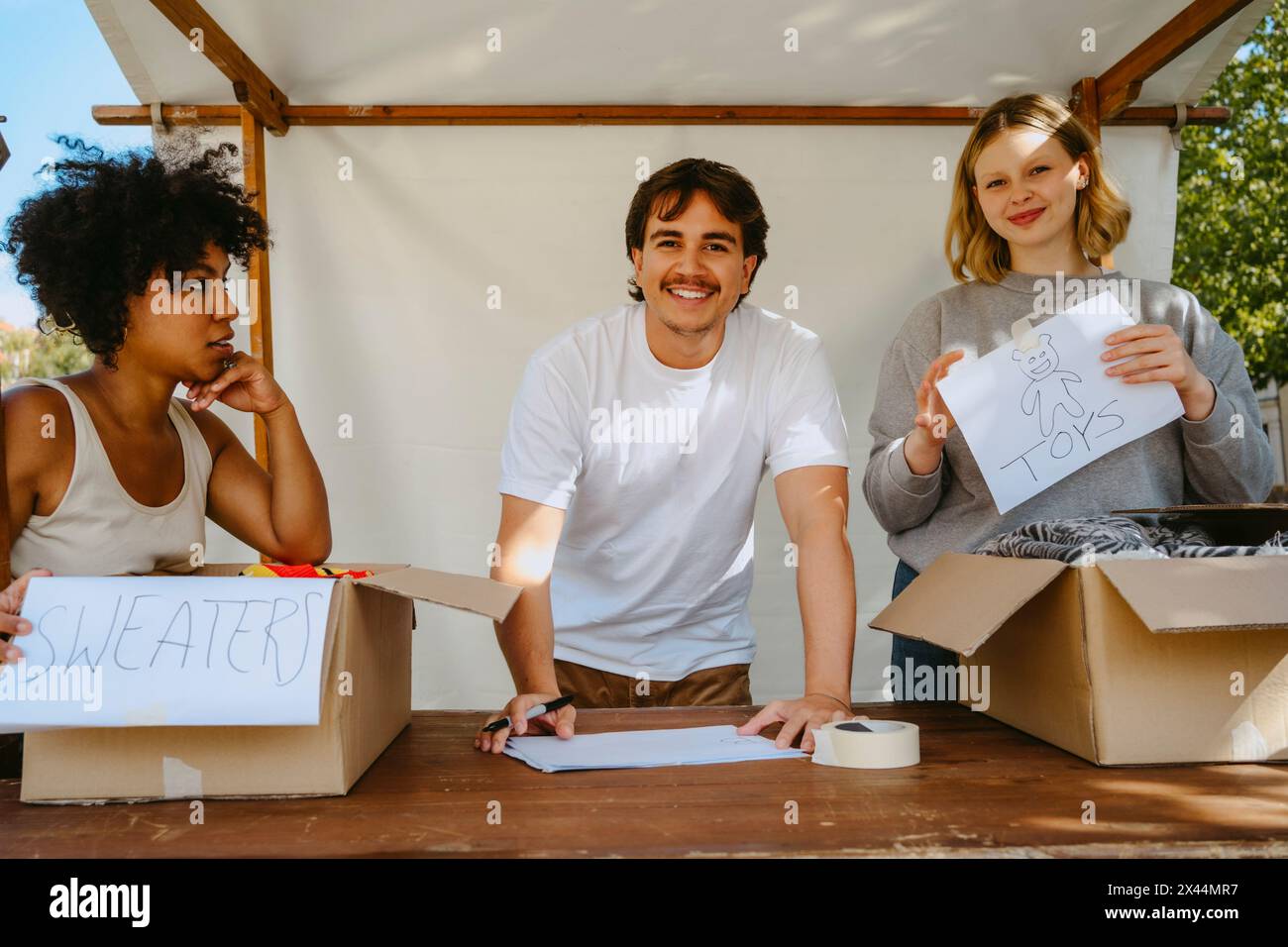 Group of smiling multiracial volunteers labeling boxes with name tags ...