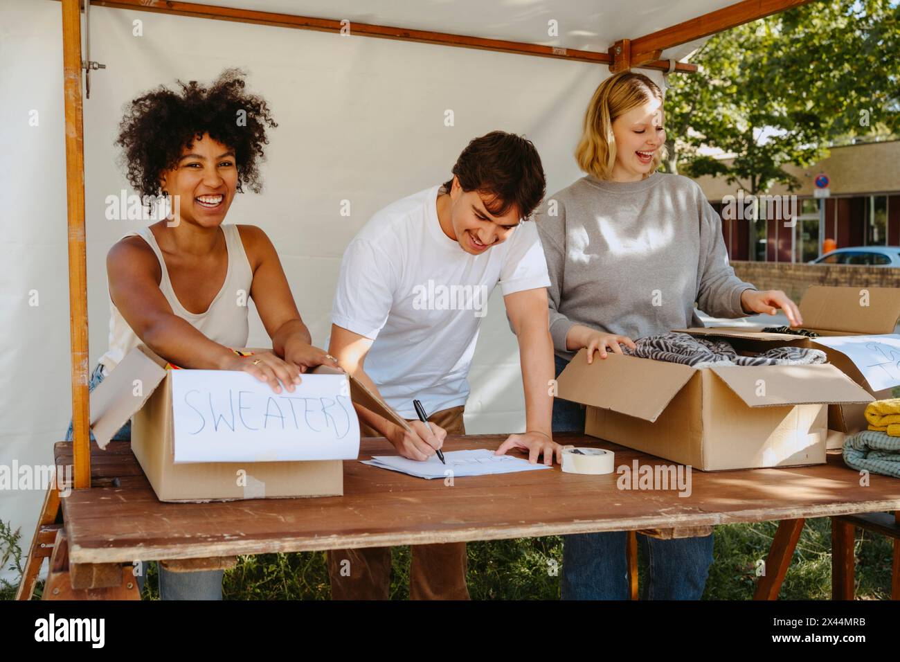 Portrait of happy female volunteers labeling boxes with colleagues ...