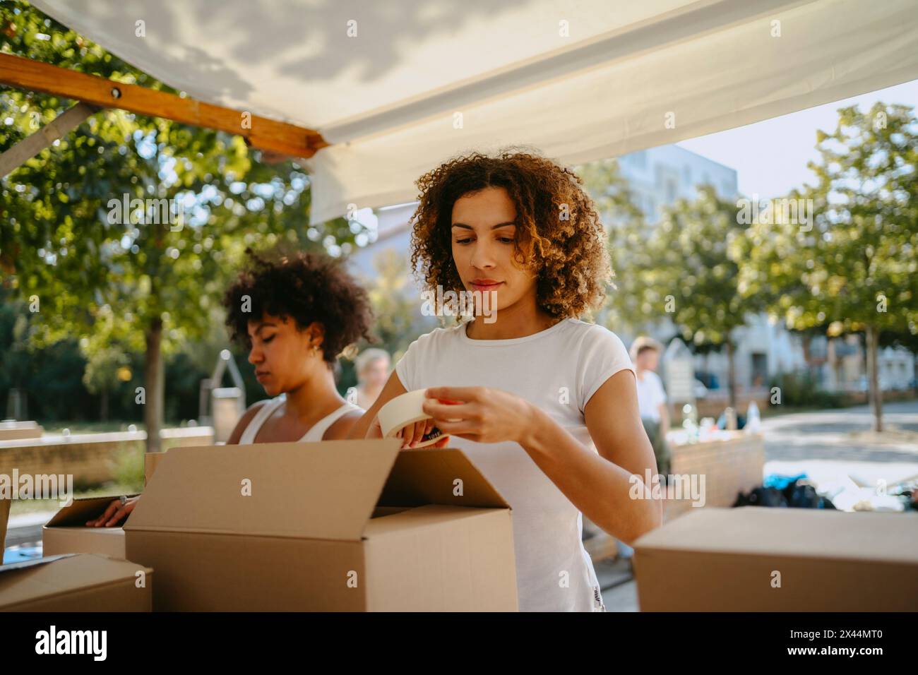 Female volunteer packing boxes with adhesive tape at community center ...