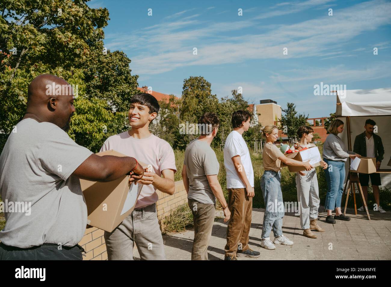 Group of multiracial male and female volunteers passing donation boxes ...