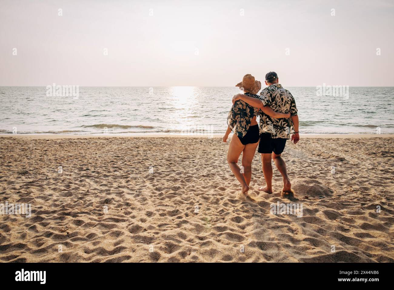 Carefree senior couple walking with arms around on sand at beach Stock ...