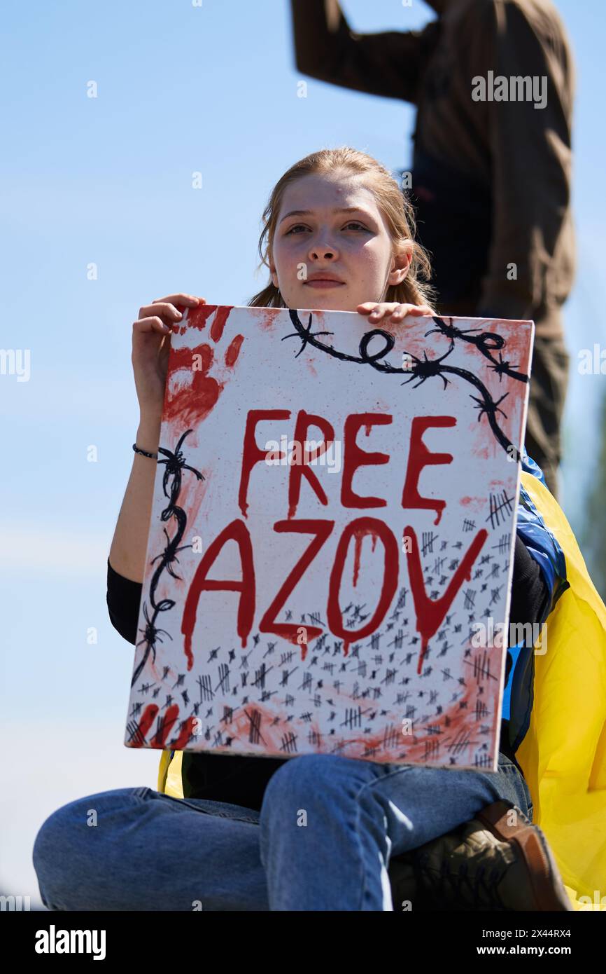 Young Ukrainian girl sitting with a sing "Free Azov" on a public ...