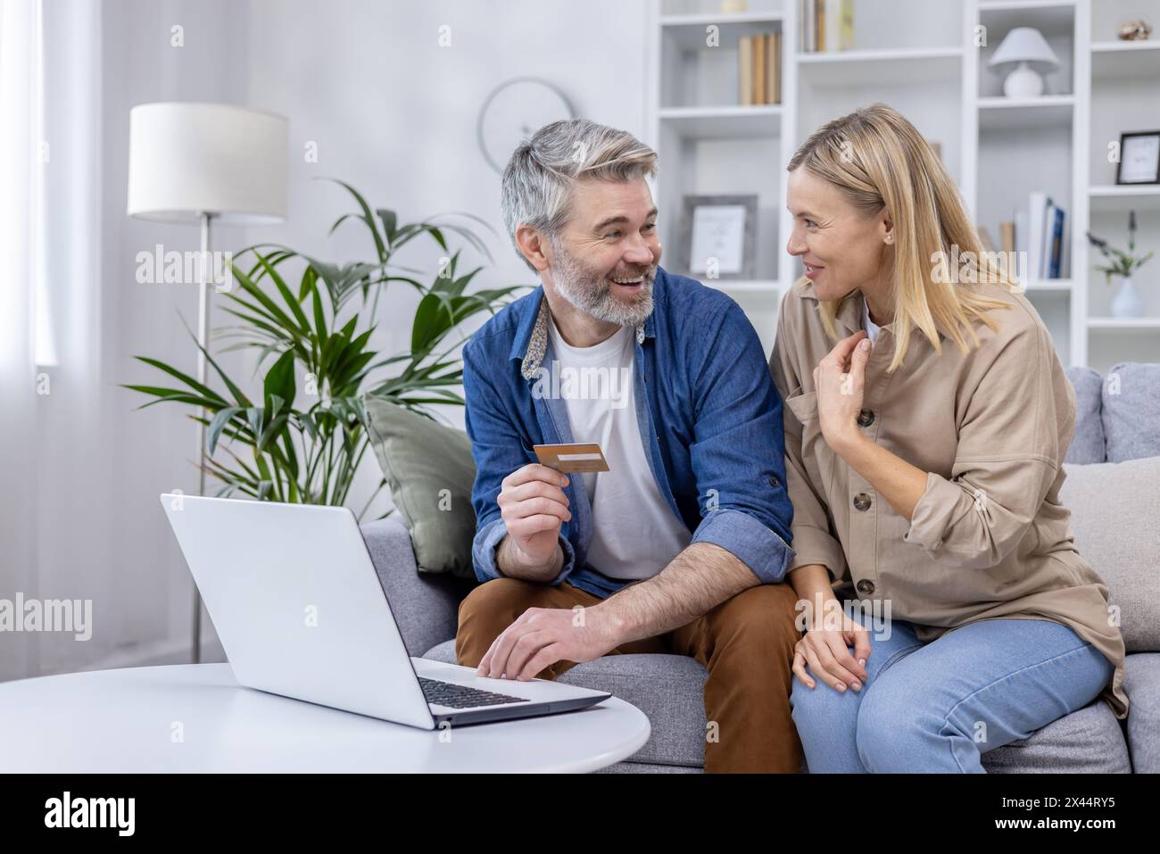 An affectionate mature couple enjoys a moment of online shopping in ...
