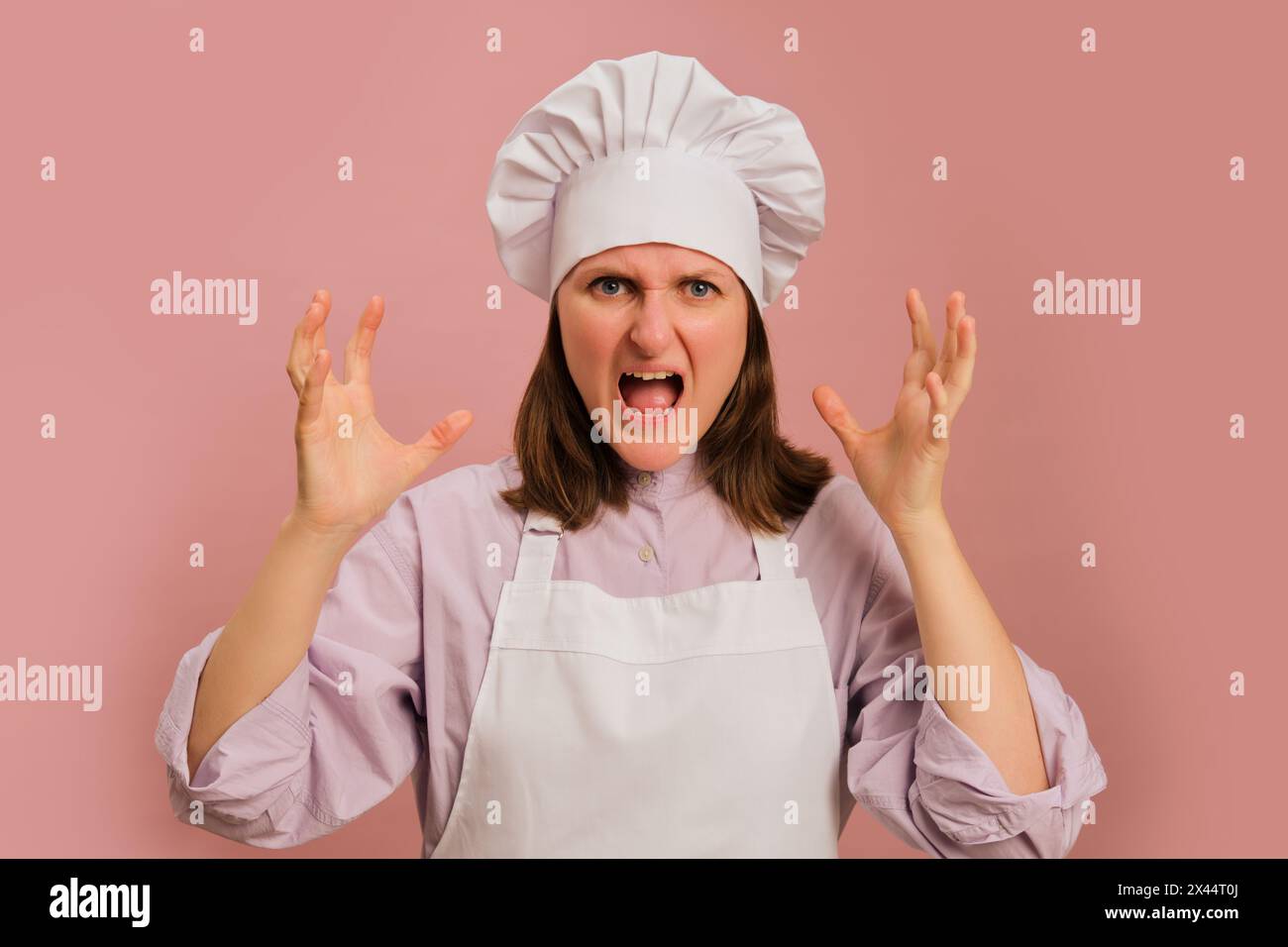 Furious woman cook on studio pink background. Portrait of a female ...