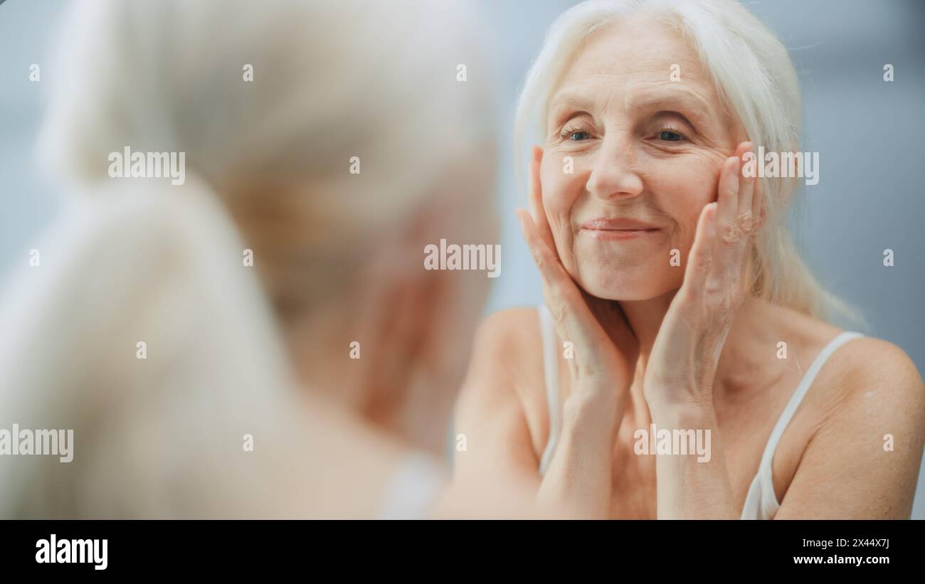 Beautiful Senior Woman Looks into Bathroom Mirror Touches Her Face, Happily Smiles, Enjoy Her ...