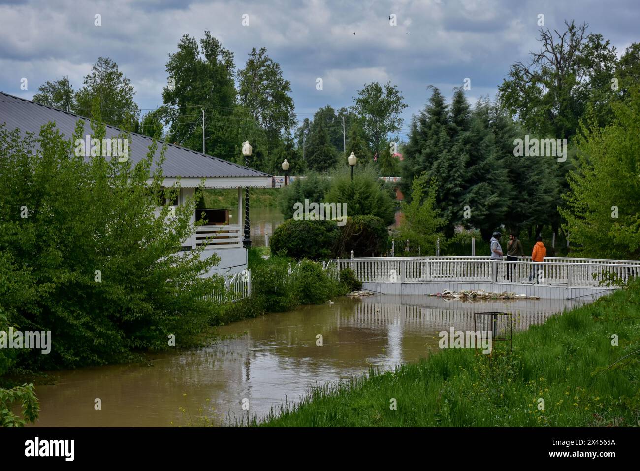 Commuters stand on a flooded wooden-footbridge as river Jhelum flows ...