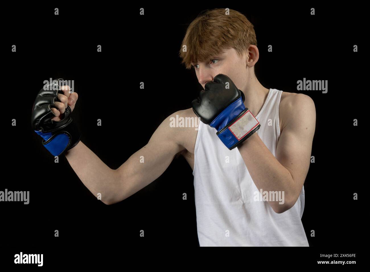 A 15 year old male teenager boxer, against a black background, wearing ...