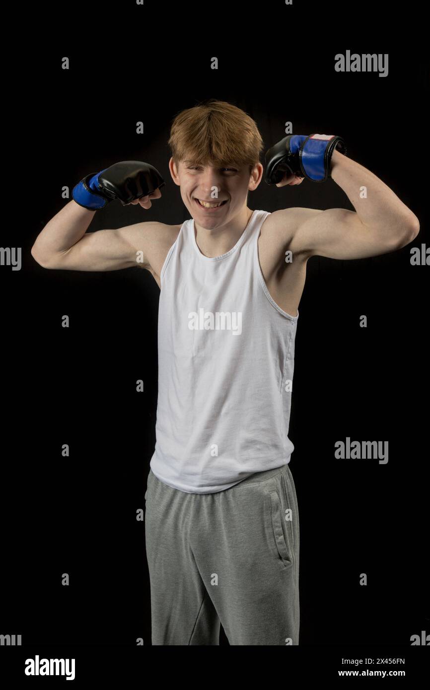 A 15 year old male teenager boxer, against a black background, wearing ...
