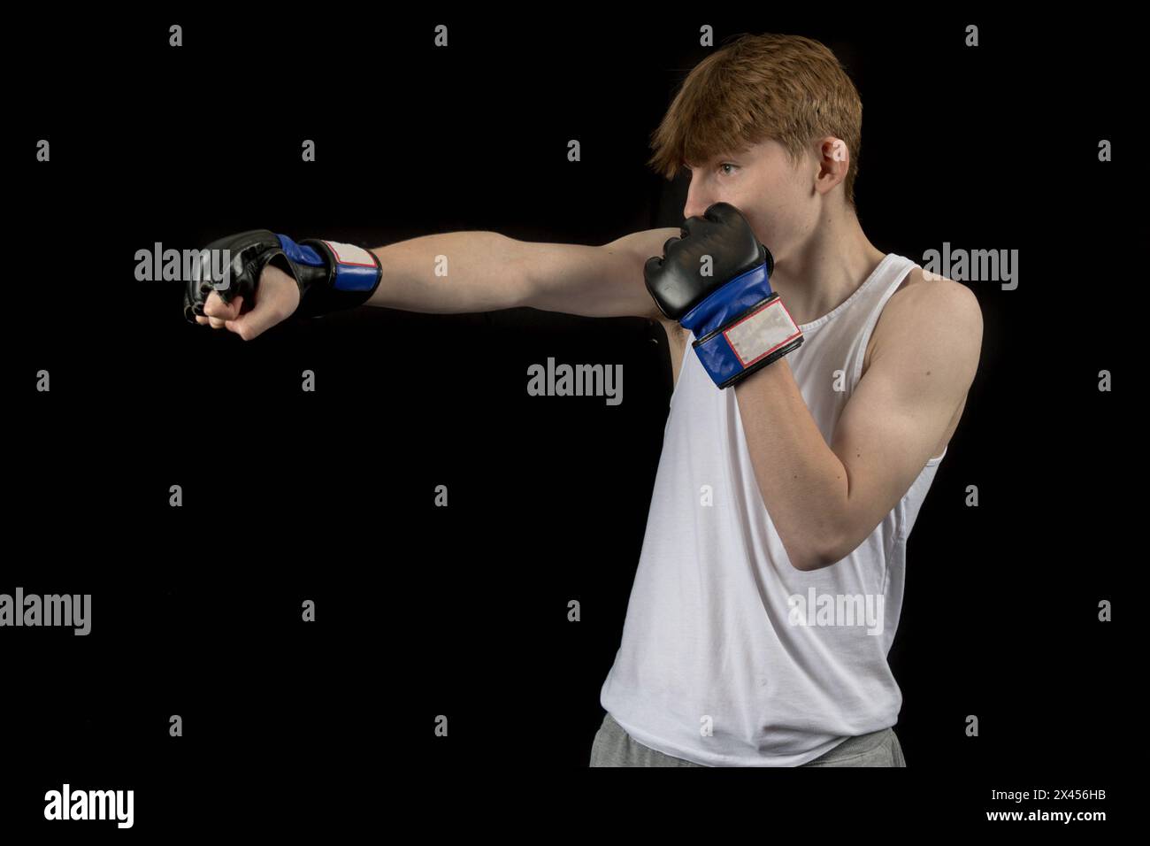 A 15 year old male teenager boxer, against a black background, wearing ...