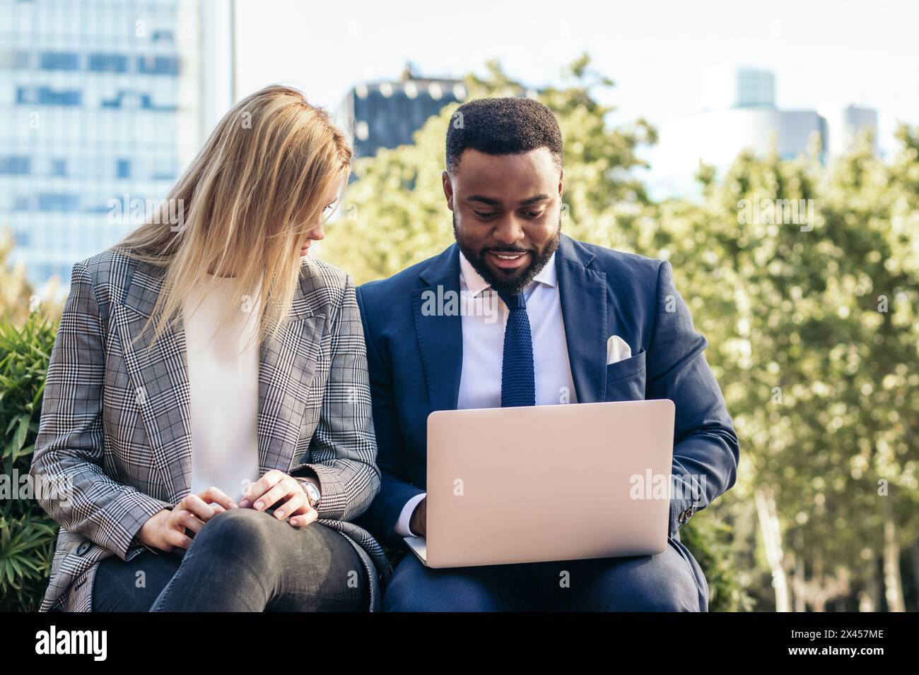 Business colleagues in suits working with laptop sitting outdoors Stock ...