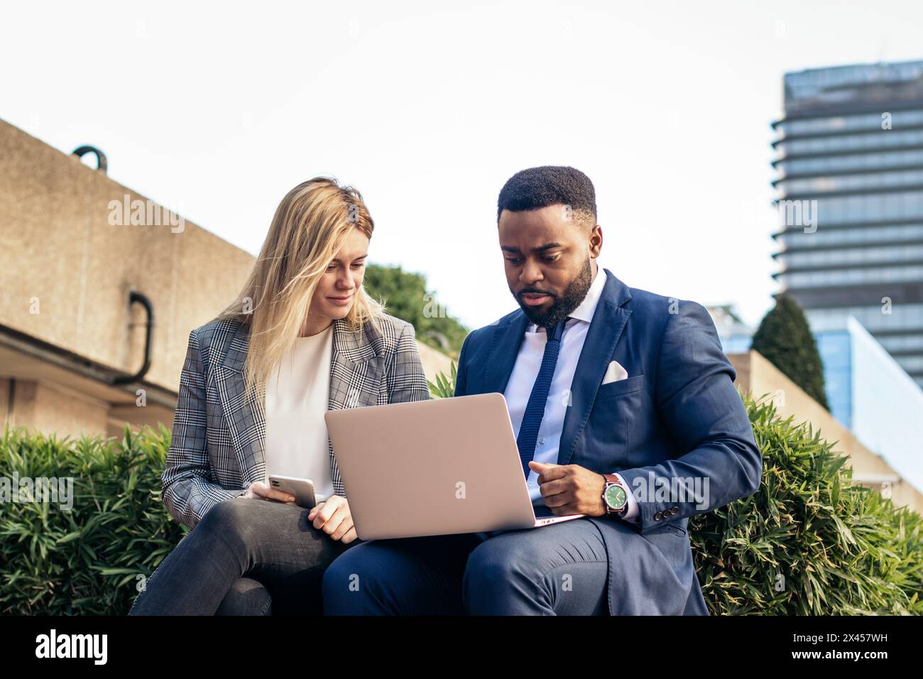 Business colleagues in suits working with laptop sitting outdoors Stock ...