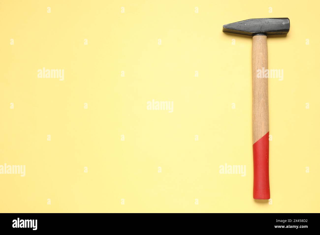 New hammer with wooden handle on yellow background, top view. Space for ...