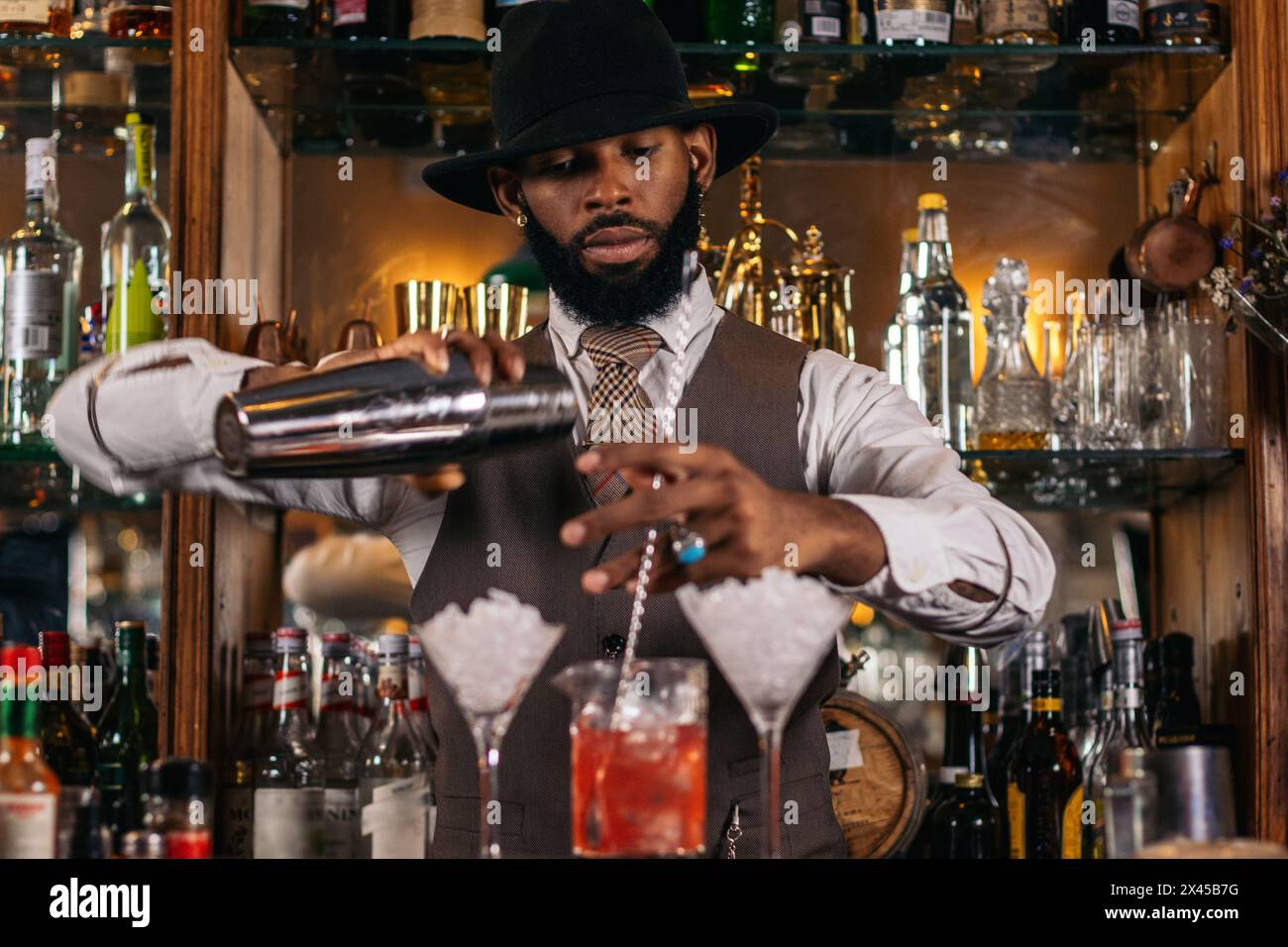 Black bartender preparing a cocktail in a traditional cocktail bar ...