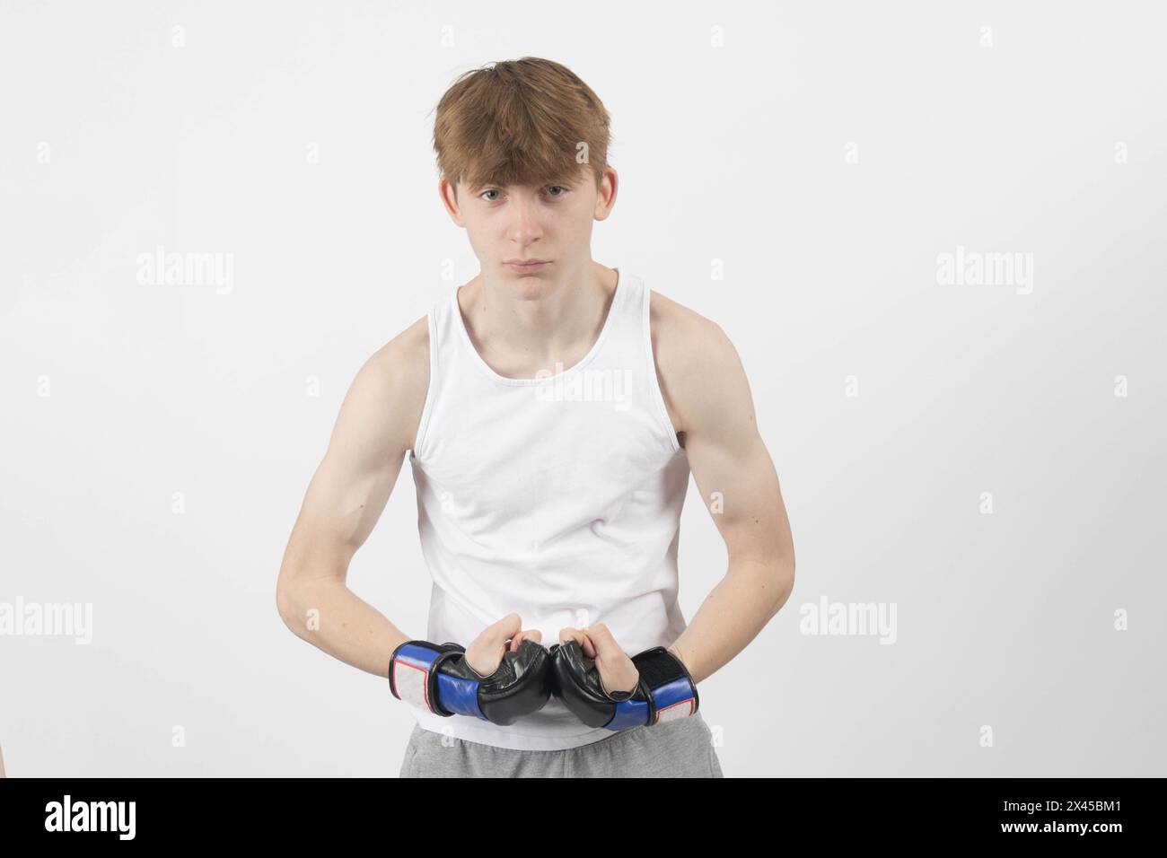 A 15 year old male teenager boxer, wearing a sleeveless top, flexing ...