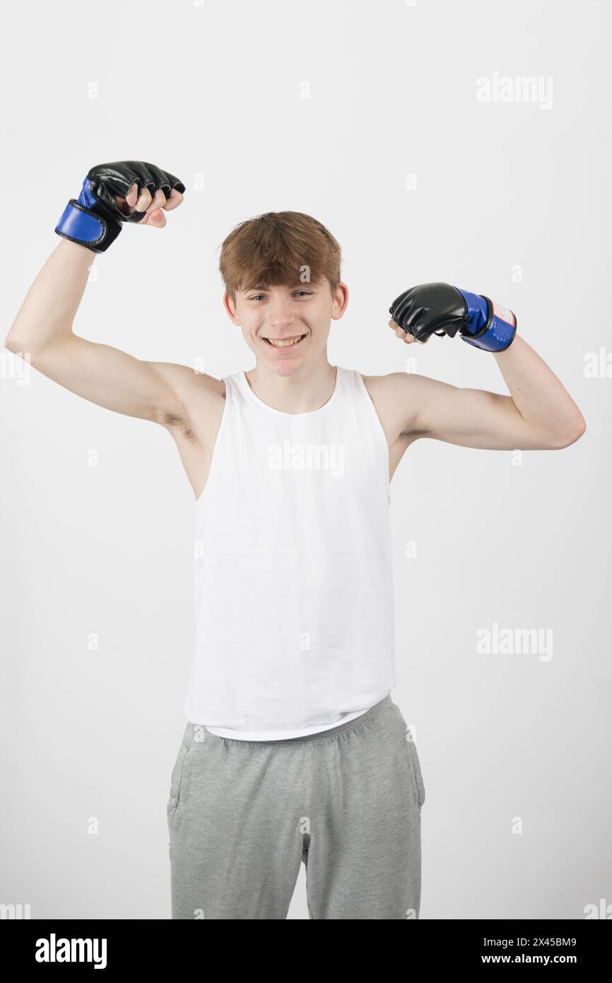A 15 year old male teenager boxer, wearing a sleeveless top, flexing ...