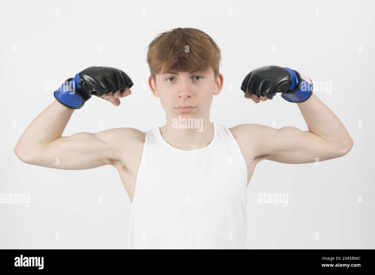A 15 year old male teenager boxer, wearing a sleeveless top, flexing ...
