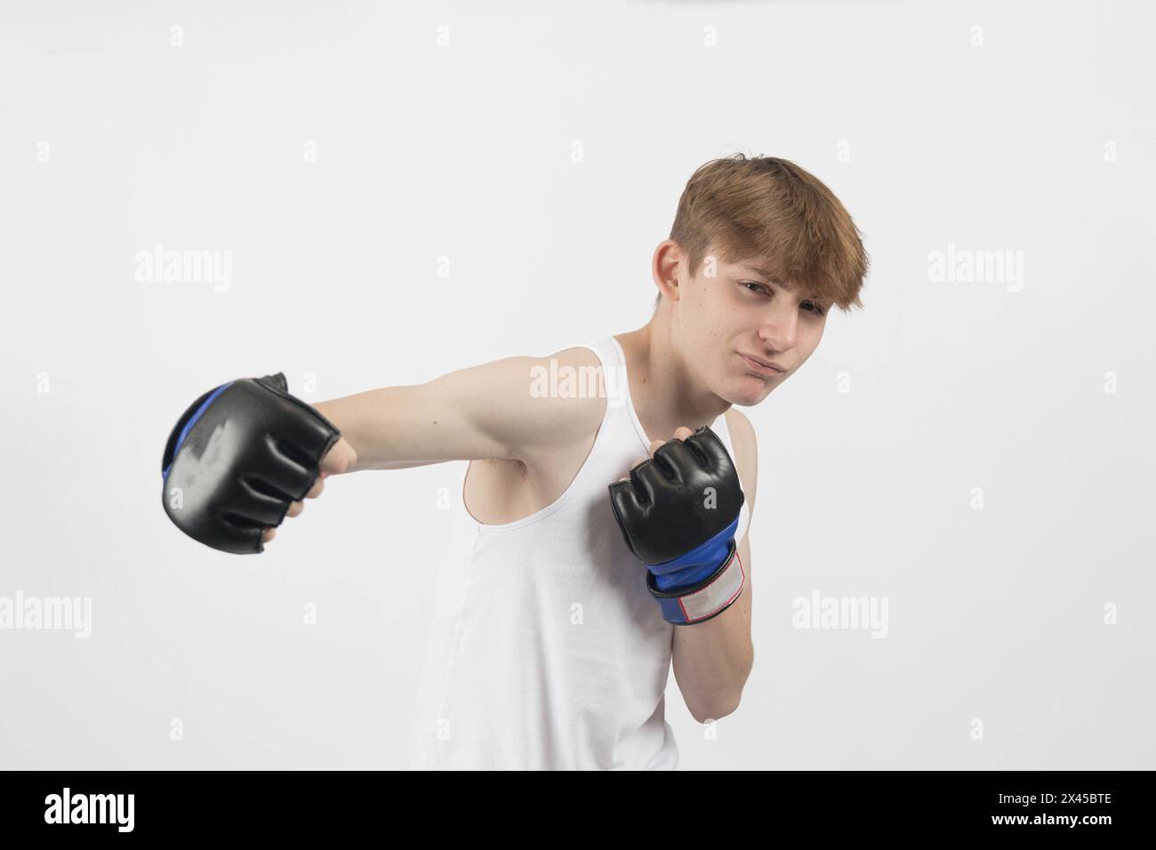 A 15 year old male teenager boxer, wearing a sleeveless top, punching ...