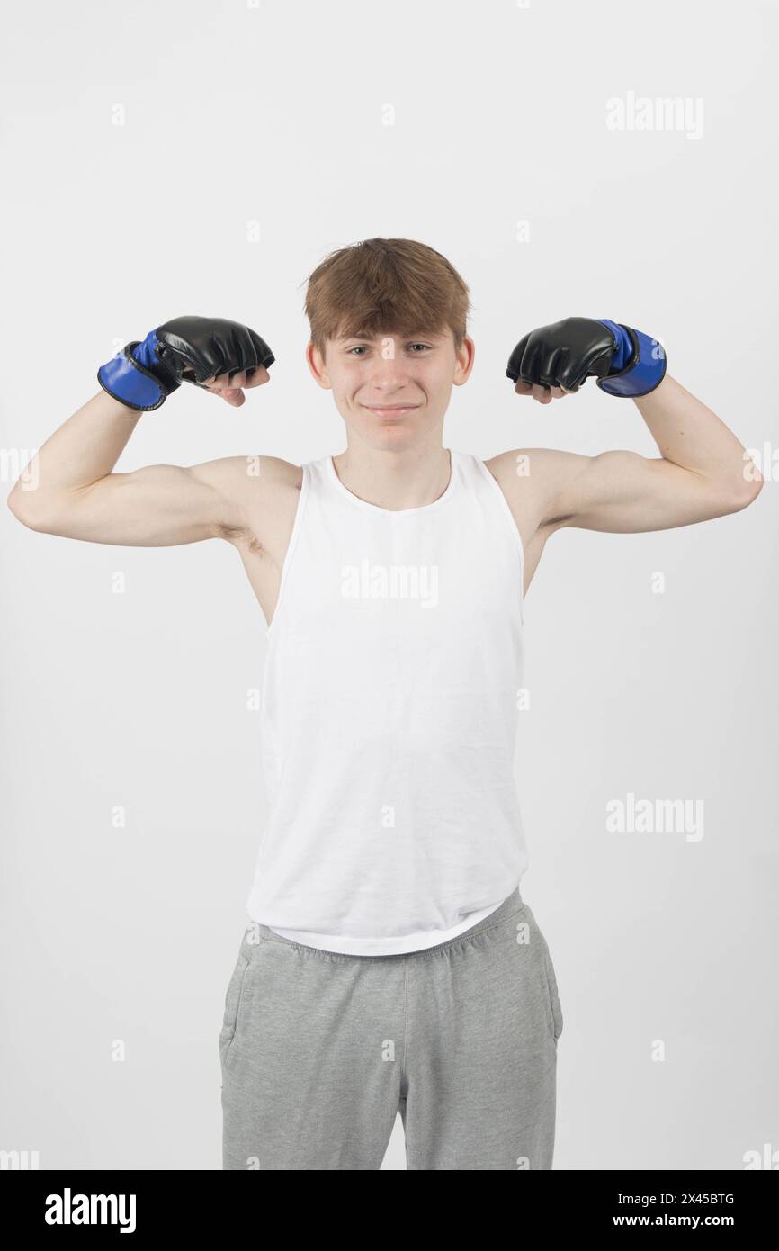 A 15 year old male teenager boxer, wearing a sleeveless top, flexing ...