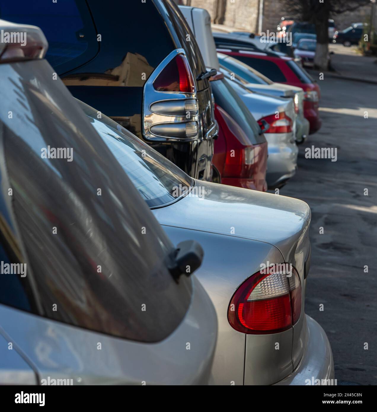 Closeup of rear, back side of golden car with other cars parking in ...