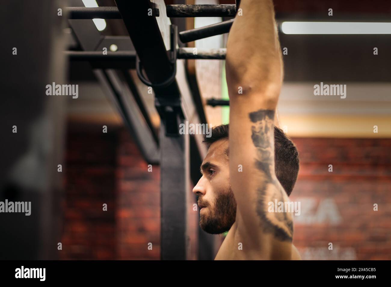 side view of a strong man doing pull ups in a gym. close-up Stock Photo ...