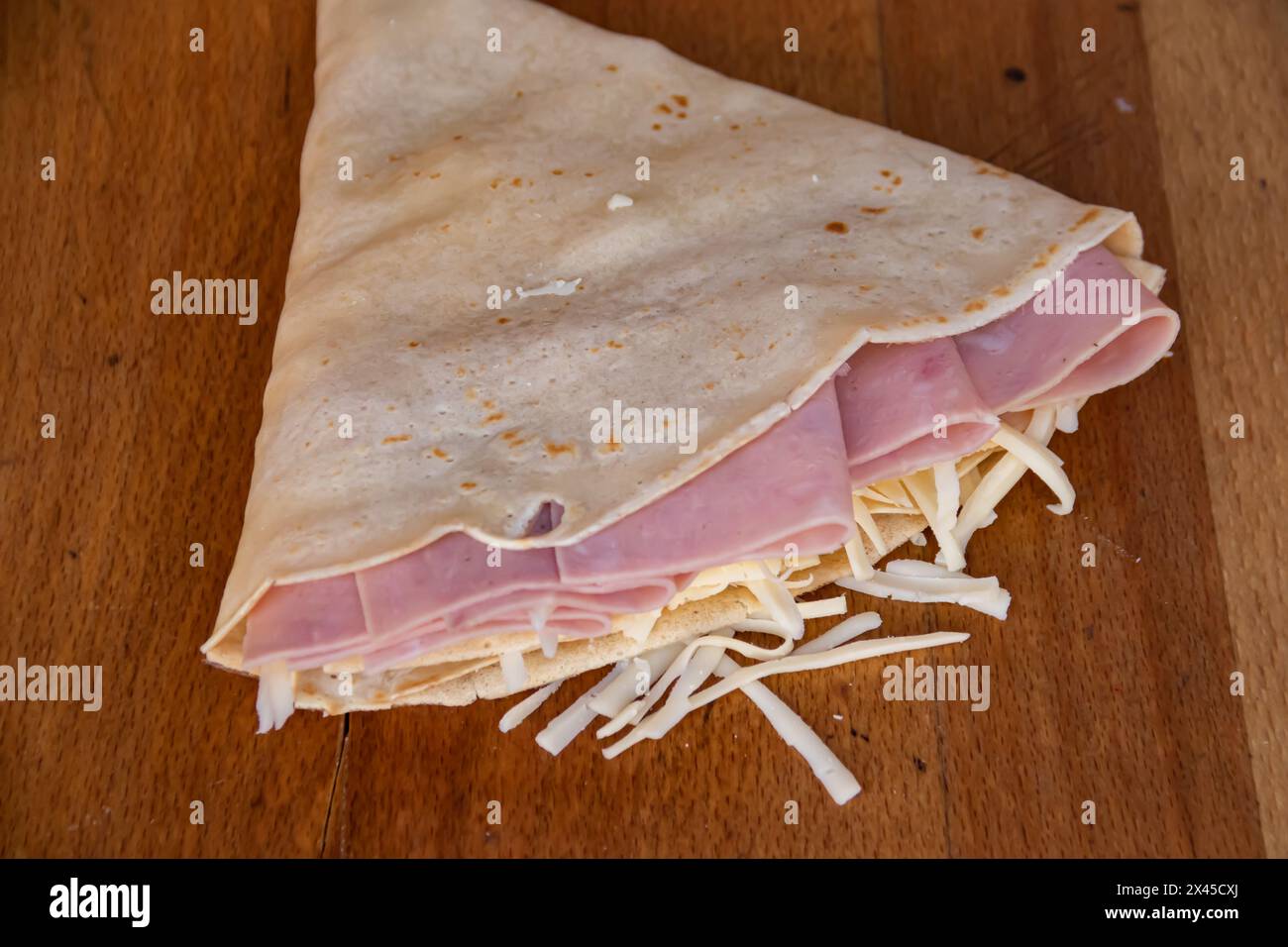 A savory pancake filled with ham and melted cheese offers a delightful ...