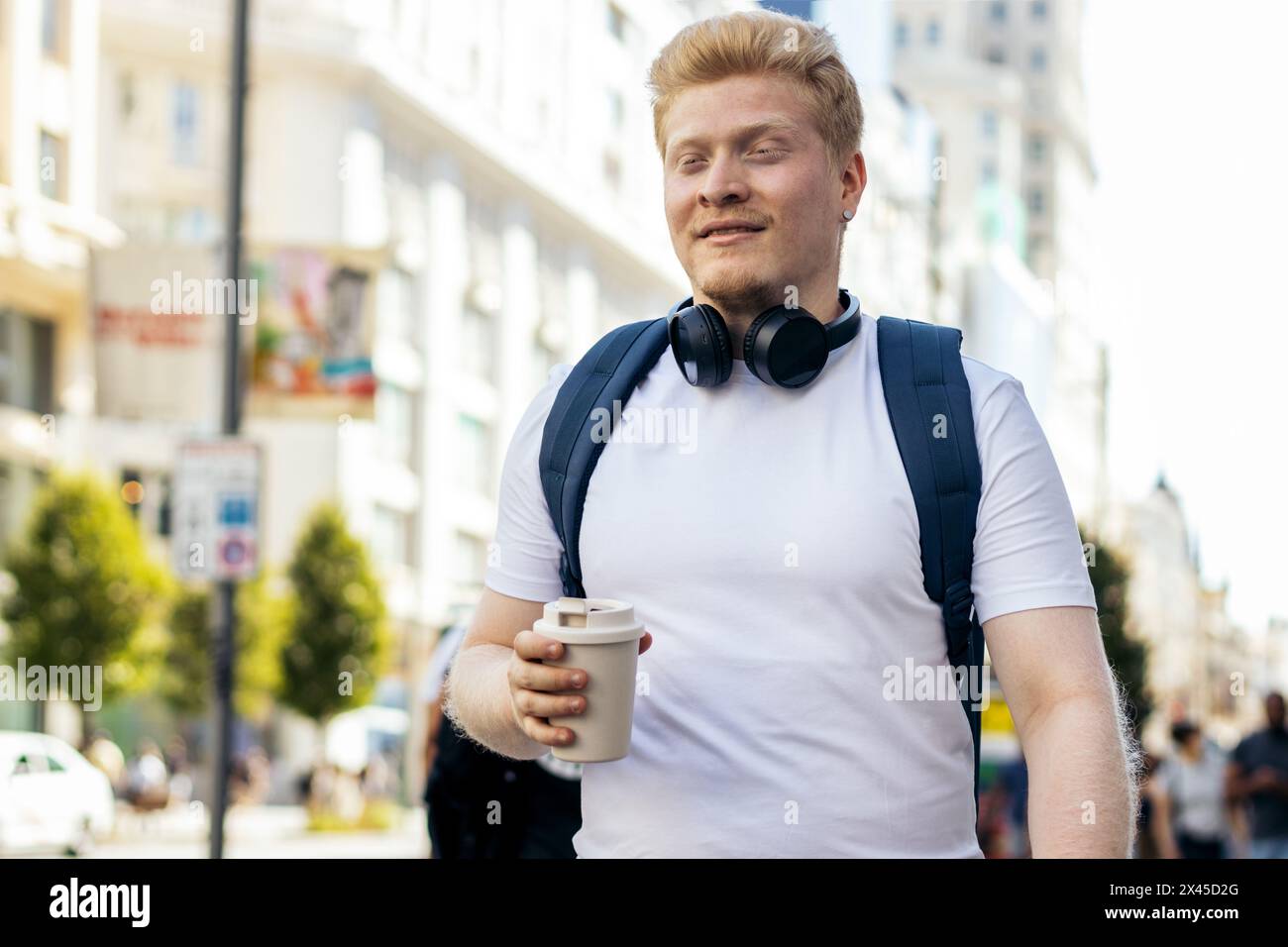 Young Latino man who is albino walking down the city street listening ...