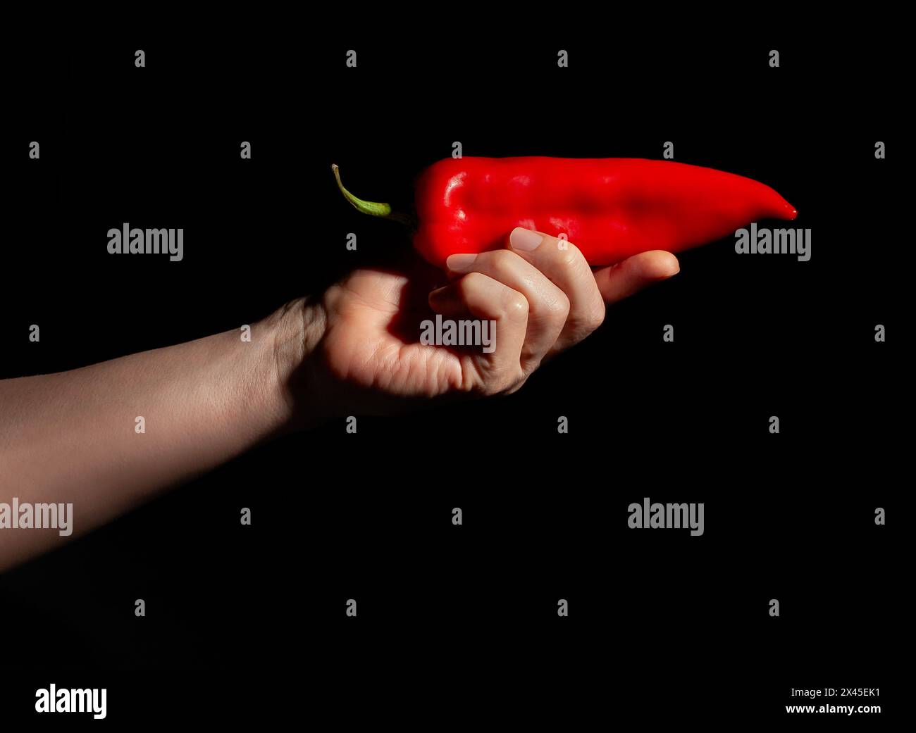 pepper in hand on black background Stock Photo - Alamy