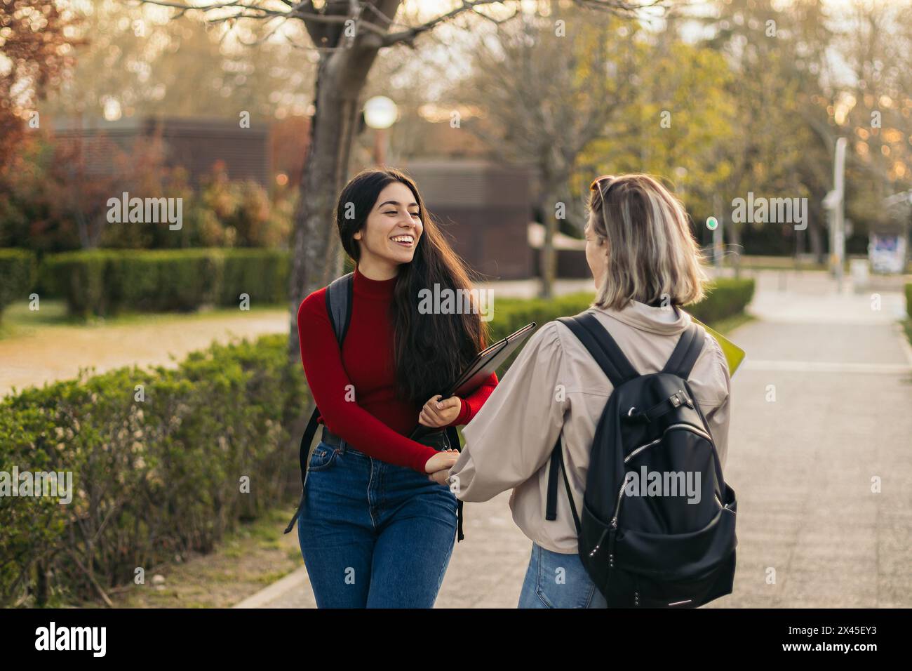 Back view of two student girls talking and laughing Stock Photo - Alamy