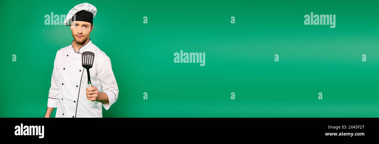 Handsome chef in white uniform holding spatula on green backdrop Stock ...