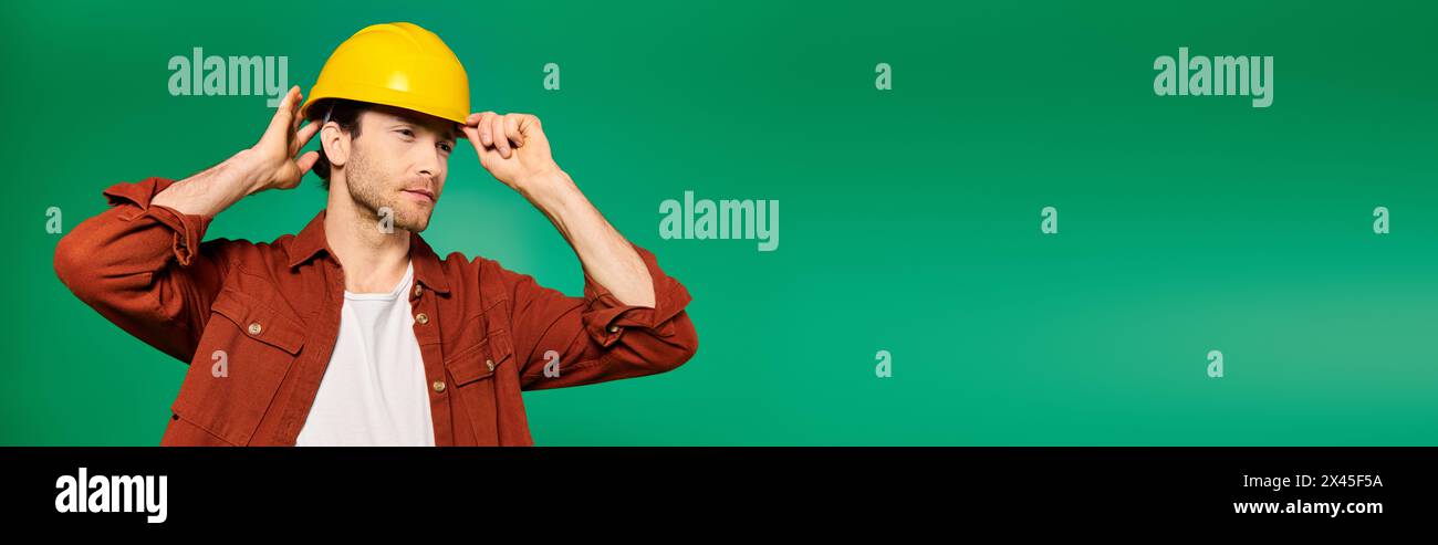 A handsome male worker in uniform poses with a yellow hard hat on a ...