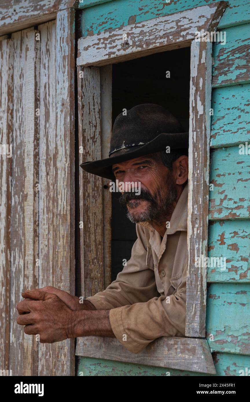 A tobacco farmer wearing a cowboy hat looking out through the window of ...