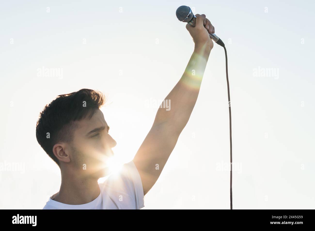 singer with the arm raised holding a microphone with sunlight reflects ...