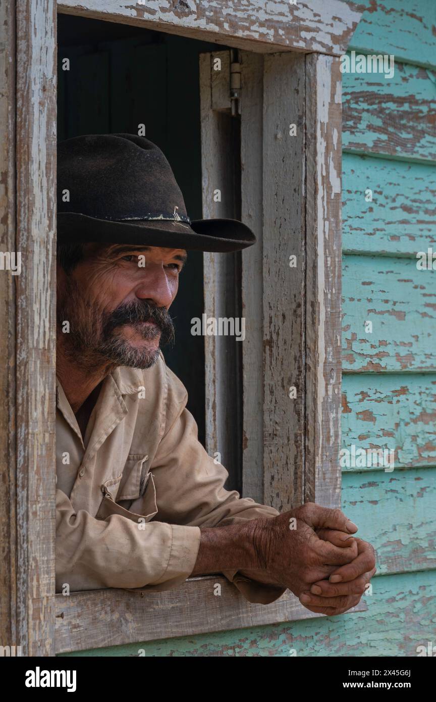 A tobacco farmer wearing a cowboy hat looking out through the window of ...