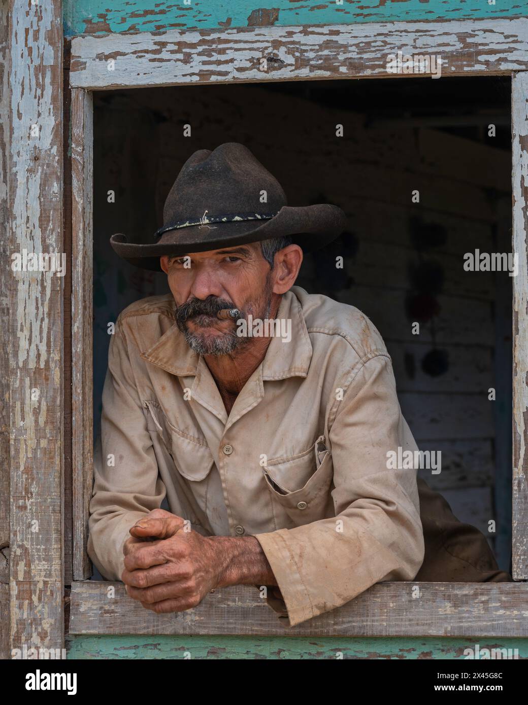 A tobacco farmer wearing a cowboy hat looking out through the window of ...