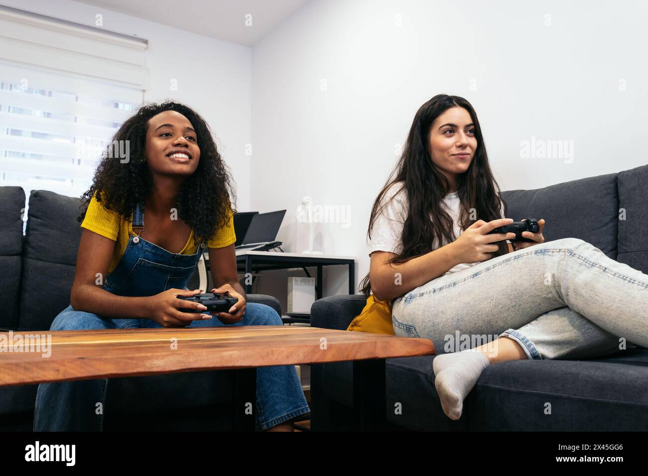 Two young women having fun with console gaming in cozy living room ...