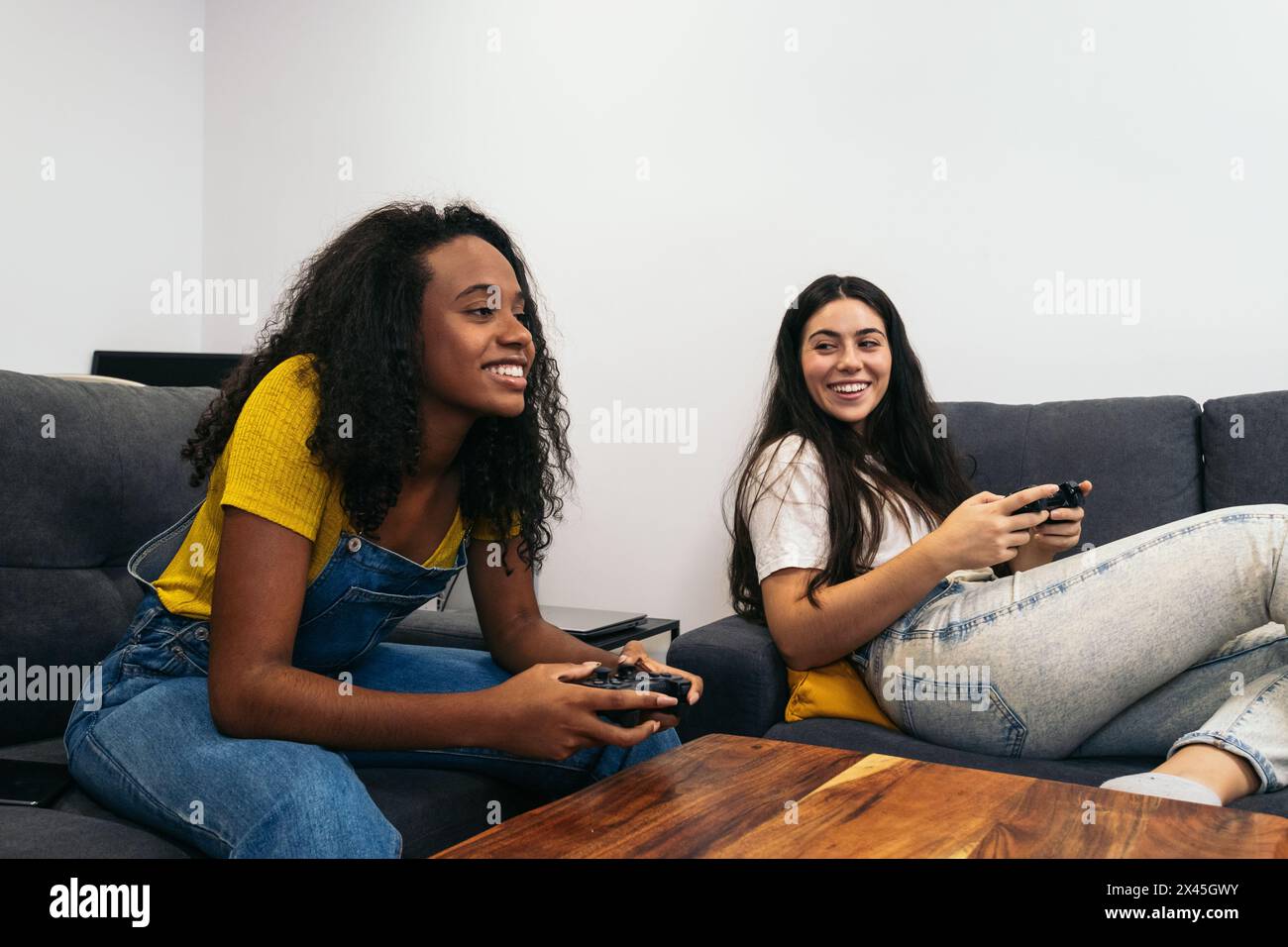 Two young women having fun with console gaming in cozy living room ...