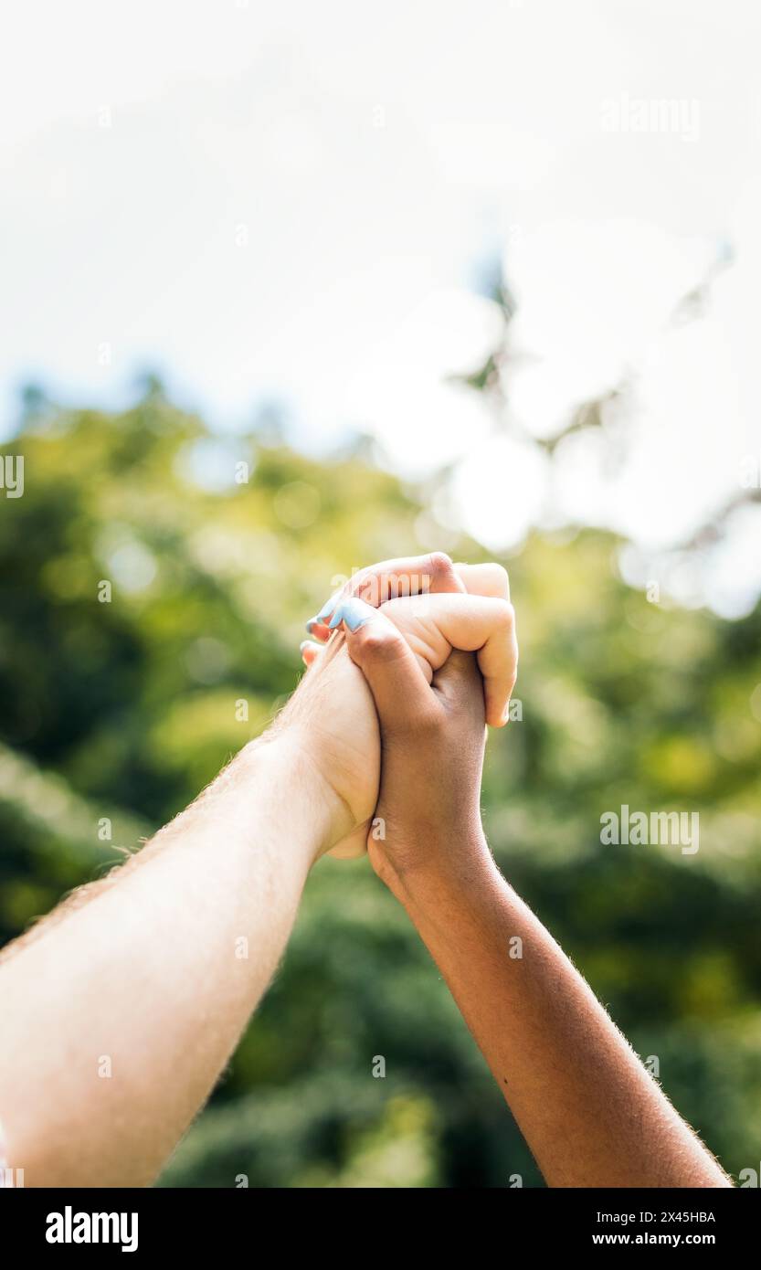 Close-up of the hands of an interracial couple interlocking their ...