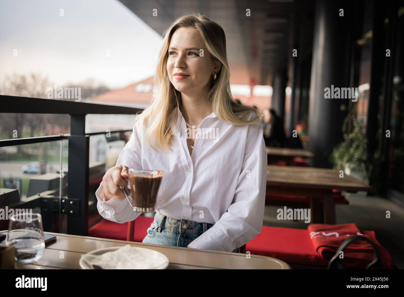 Gen z blonde woman drinks hot chocolate in summer cafe. Tasty beverage ...