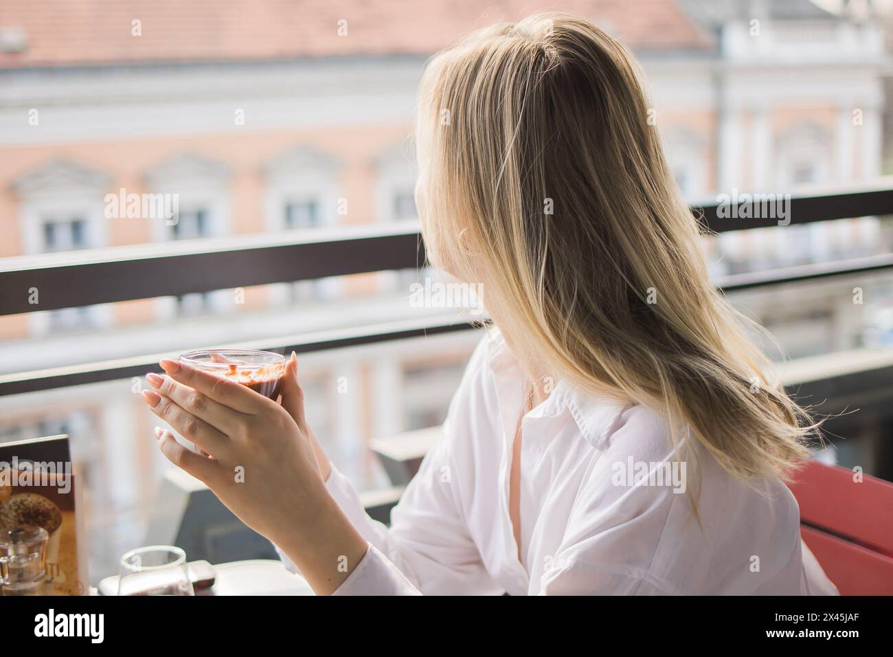 Gen z blonde woman drinks hot chocolate in summer cafe. Tasty beverage ...