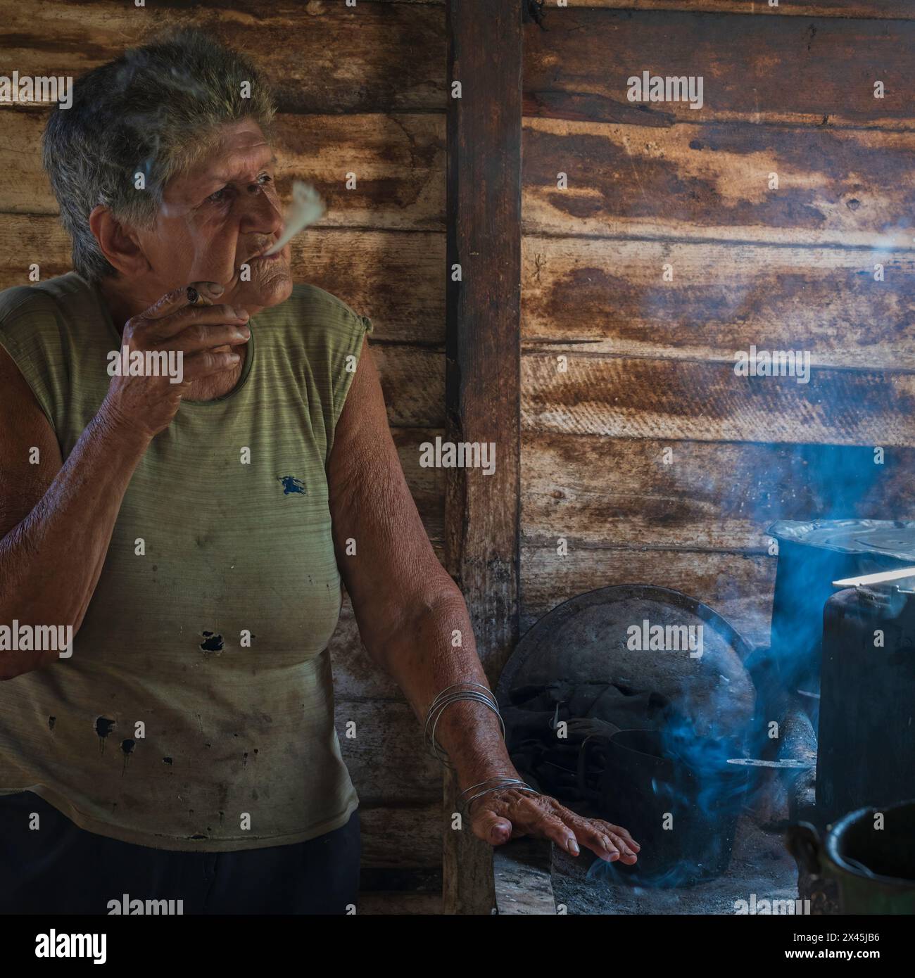 A coffee farmers wife smoking a cigar in the farmhouse while making the ...