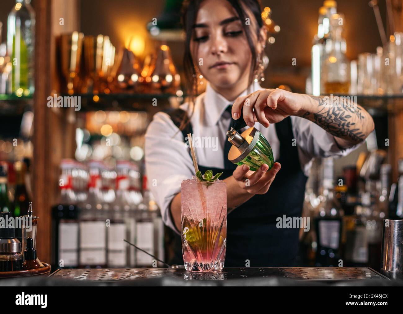 Female bartender preparing a mojito cocktail served in a tall glass in ...