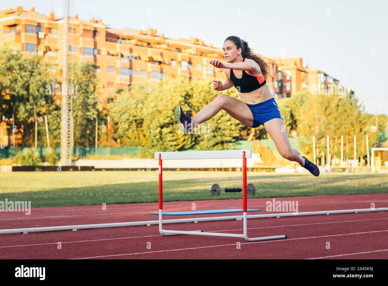 A strong woman in sports attire training for an obstacle race. She is ...