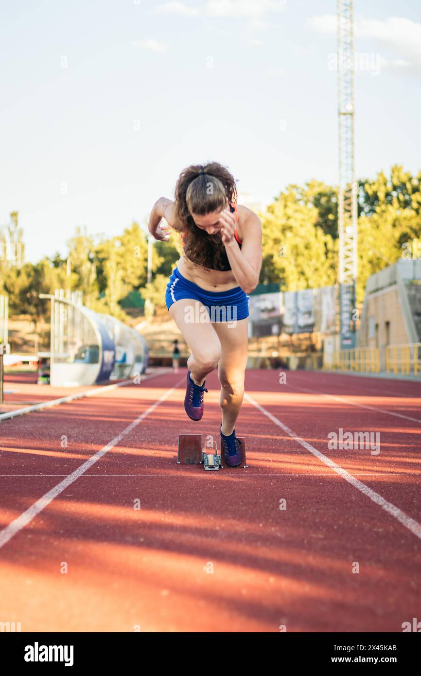 Strong woman in sports attire running fast on an athletics track Stock ...