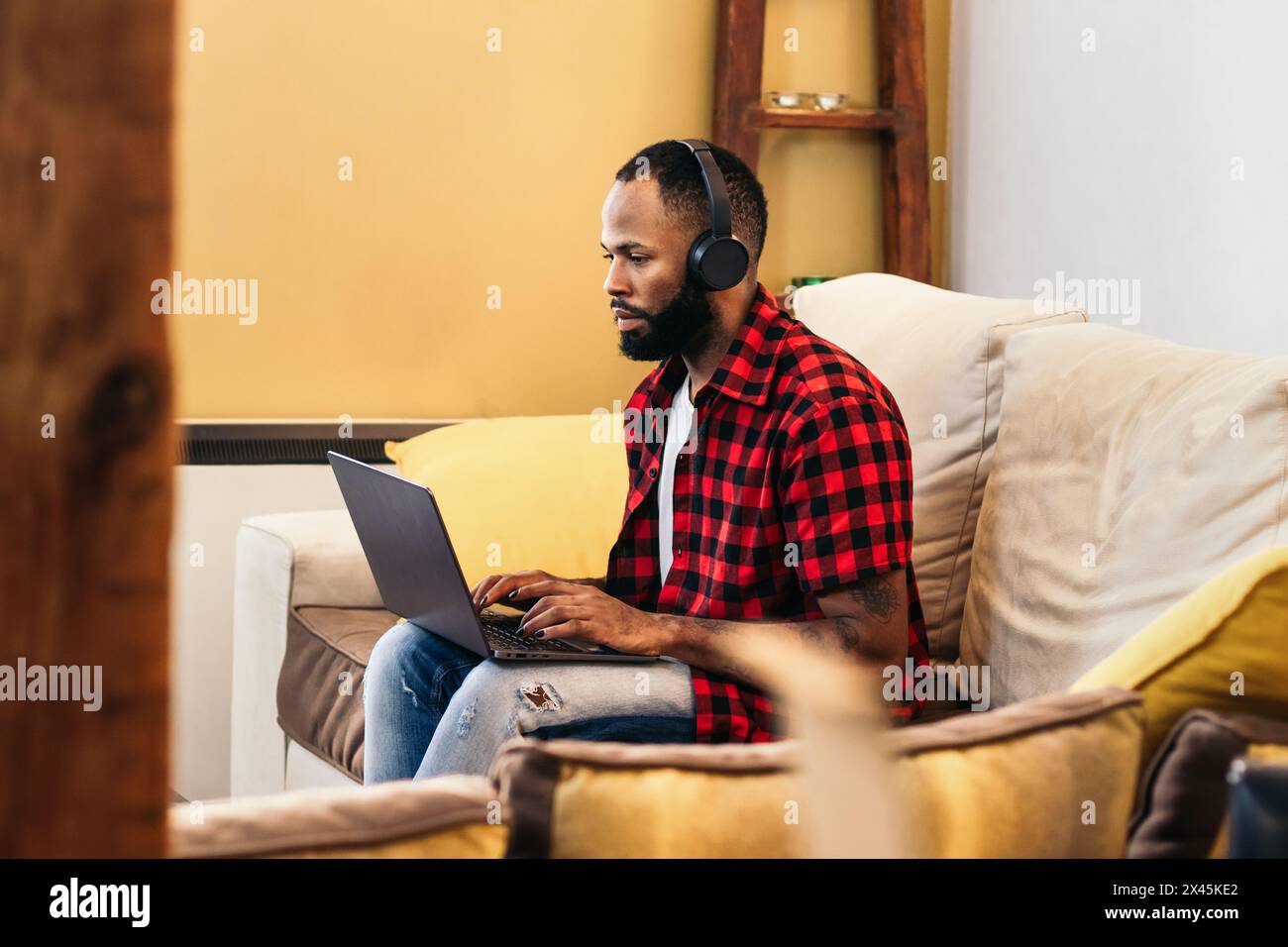 Smiling black man working remotely from home with laptop computer and ...
