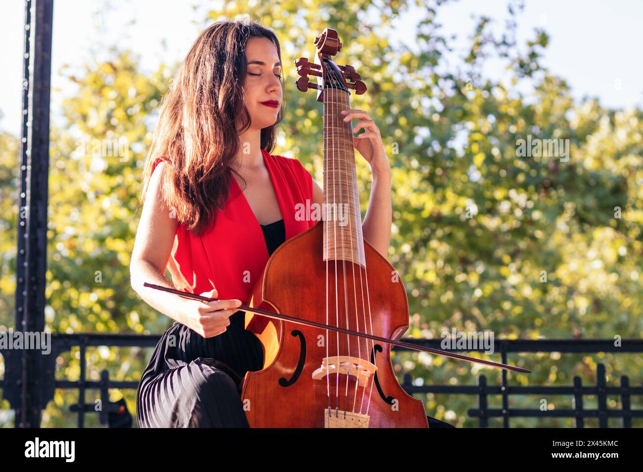Young woman giving a cello concert on an outdoor stage in a park Stock ...