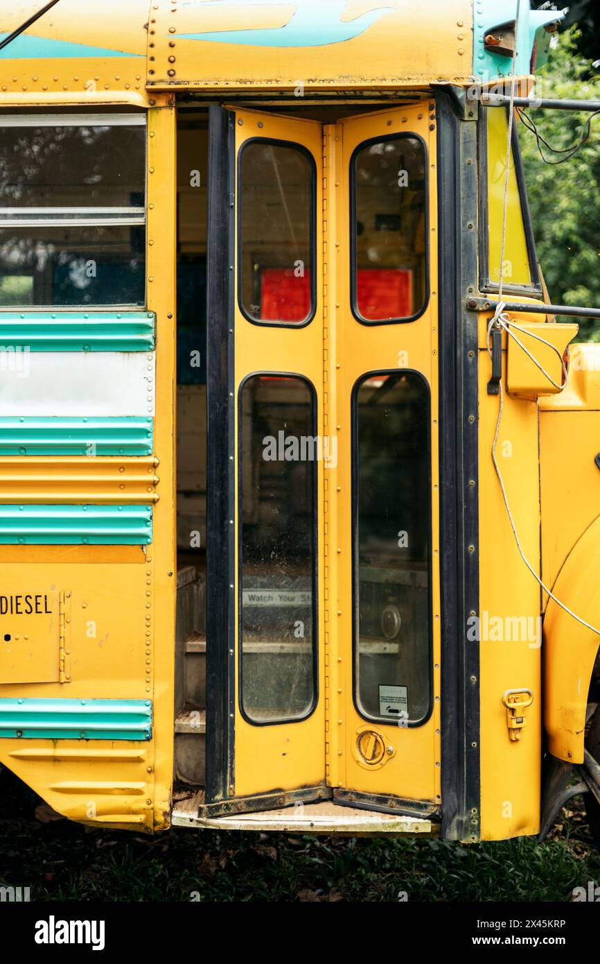 Close-up of the partially open door of an old yellow school bus. The ...