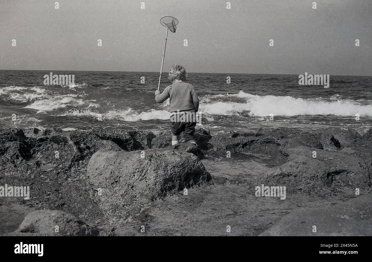 1960s, historical, a view from behind of a young boy in shorts and ...