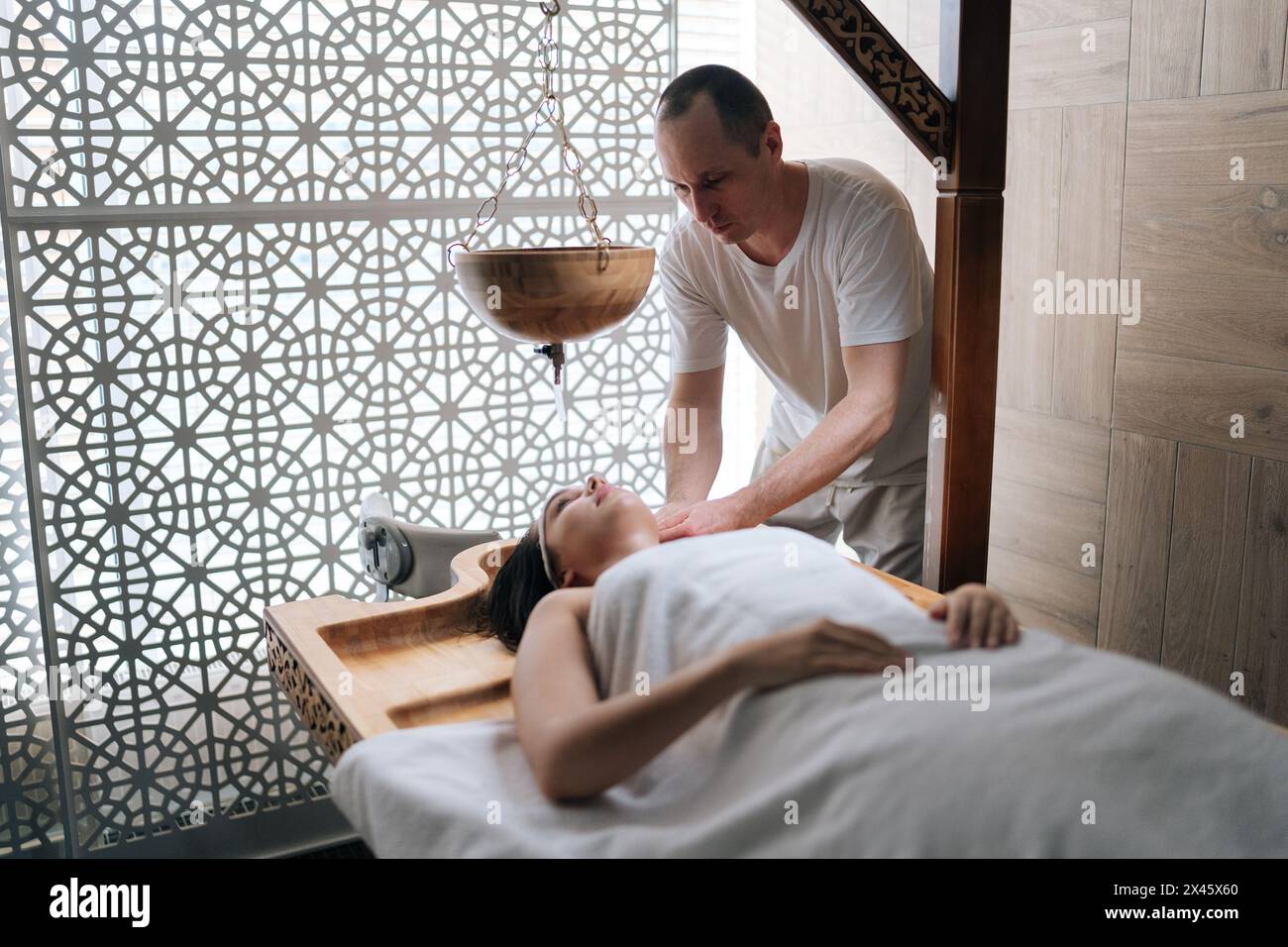 Professional spa master applying bandage to forehead of female client ...