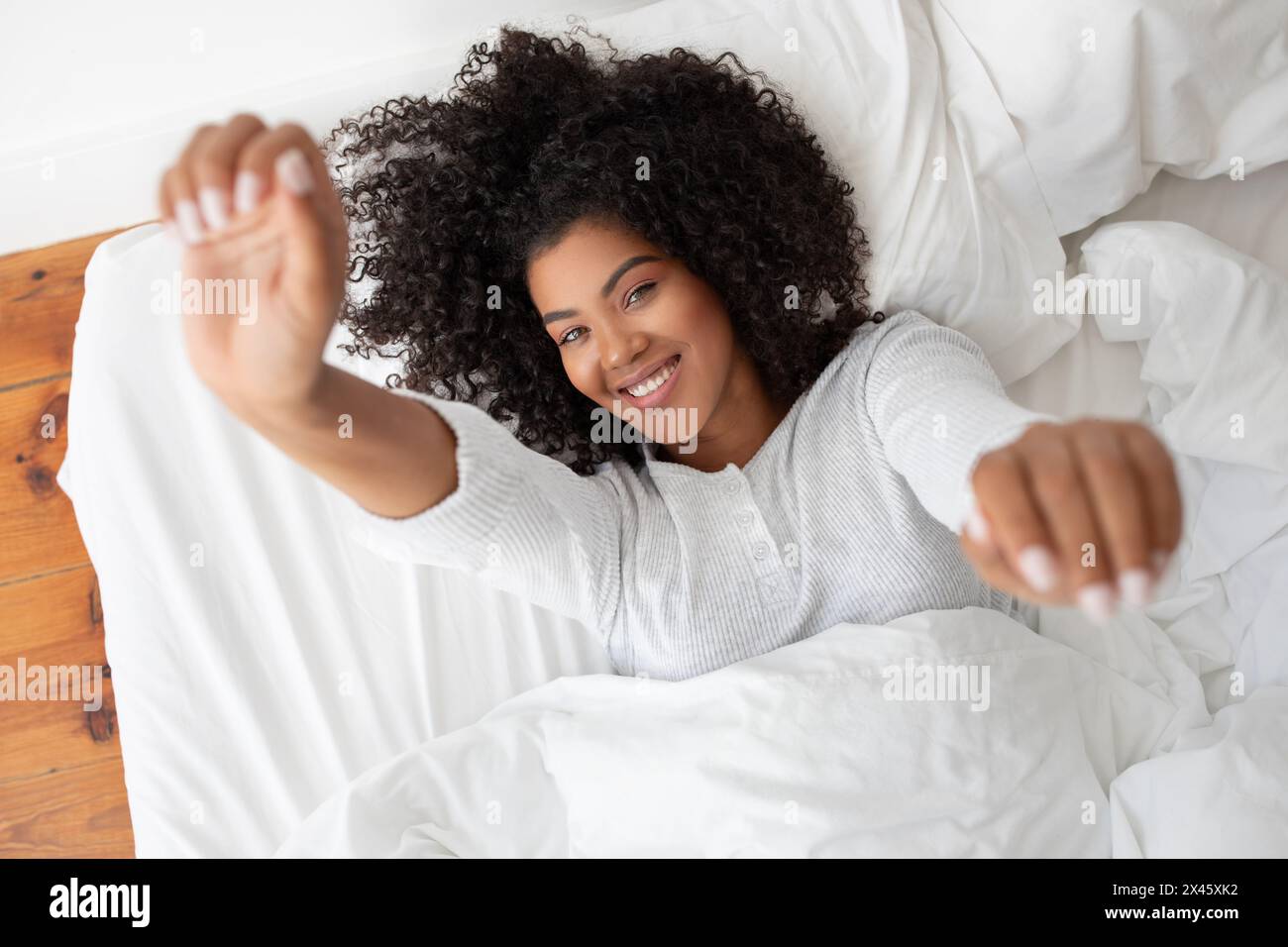 Woman Laying in Bed With White Sheets, Stretching Arms Stock Photo - Alamy
