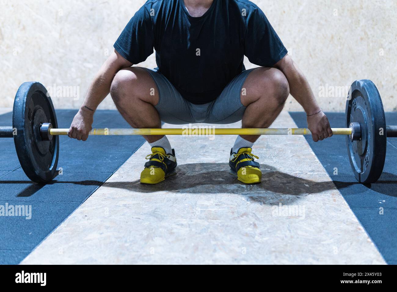 Crop anonymous strong male bodybuilder in activewear hunkering down ...